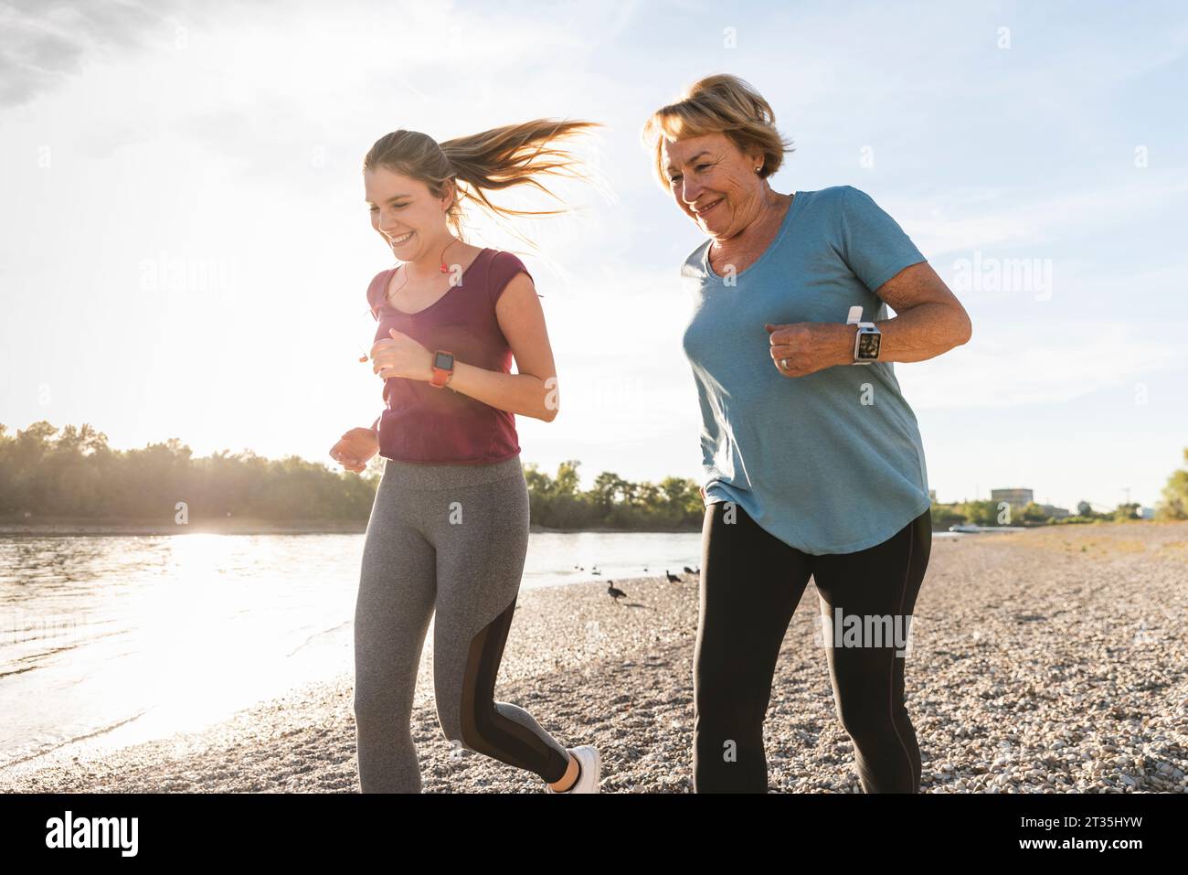 Granddaughter and grandmother having fun, jogging together at the river ...