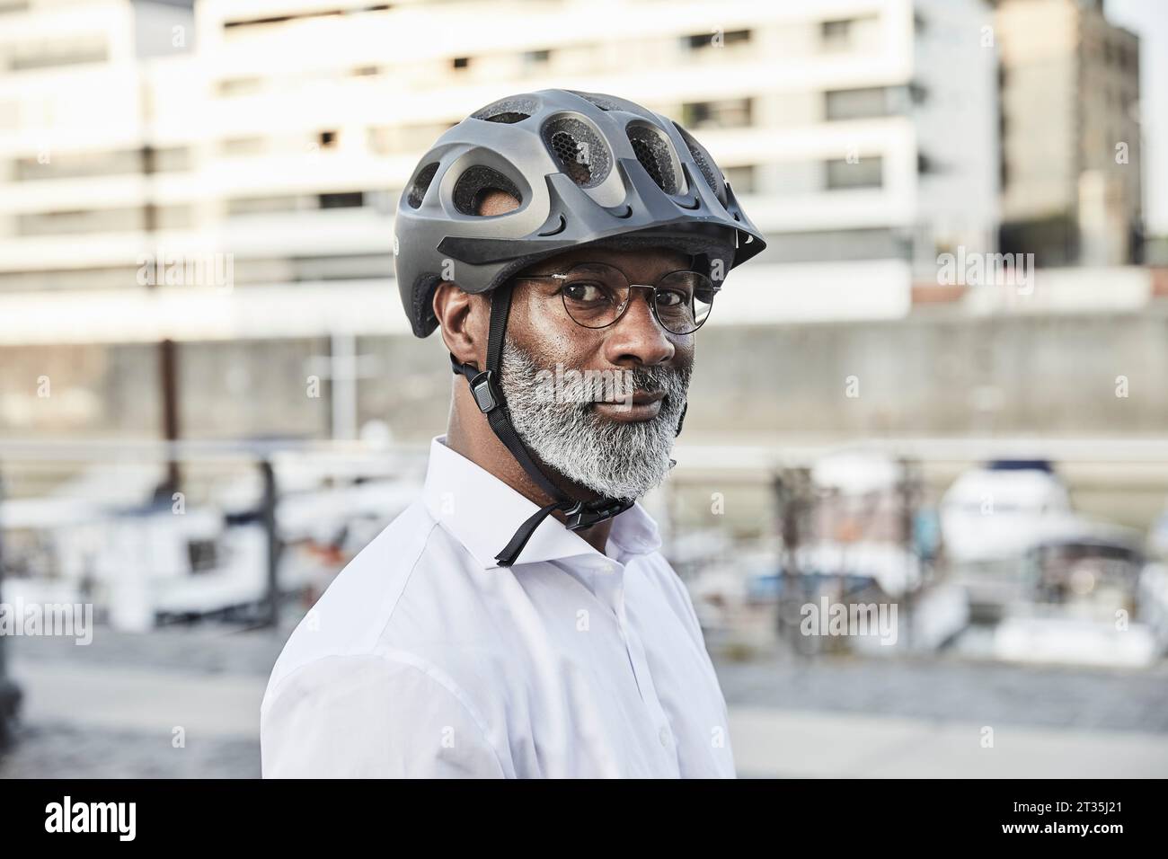 Portrait of mature businessman with grey beard wearing cycling helmet ...