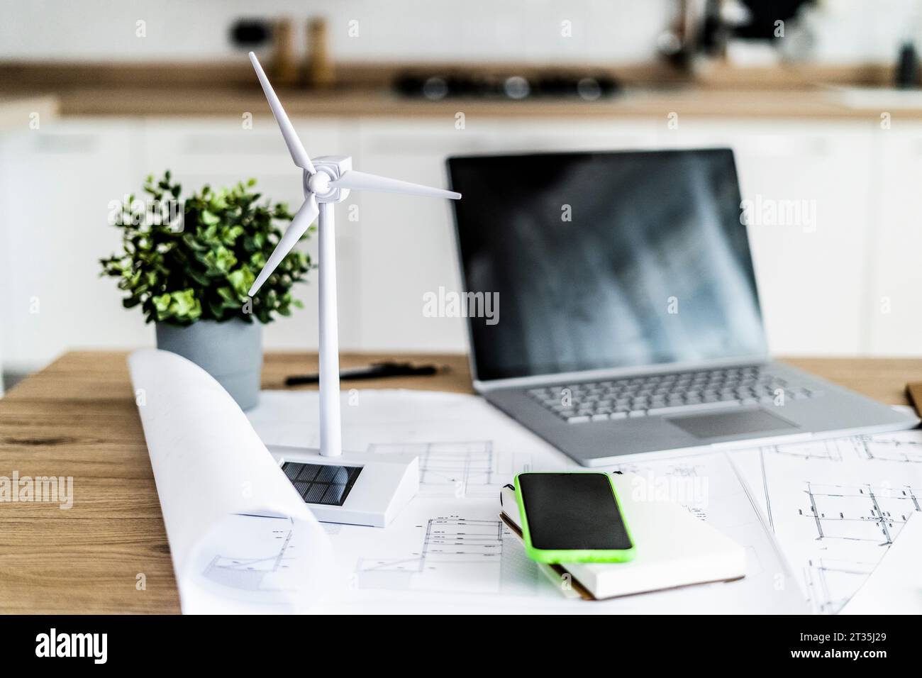 Wind turbine model, construction plan, cell phone and laptop on table ...