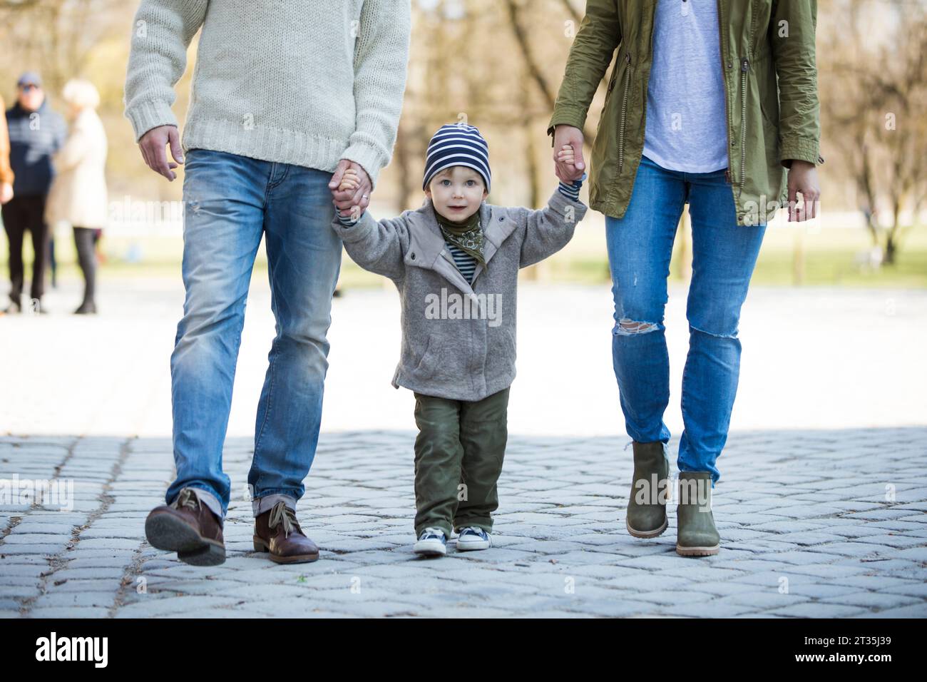 Portrait of boy walking hand in hand with parents Stock Photo - Alamy