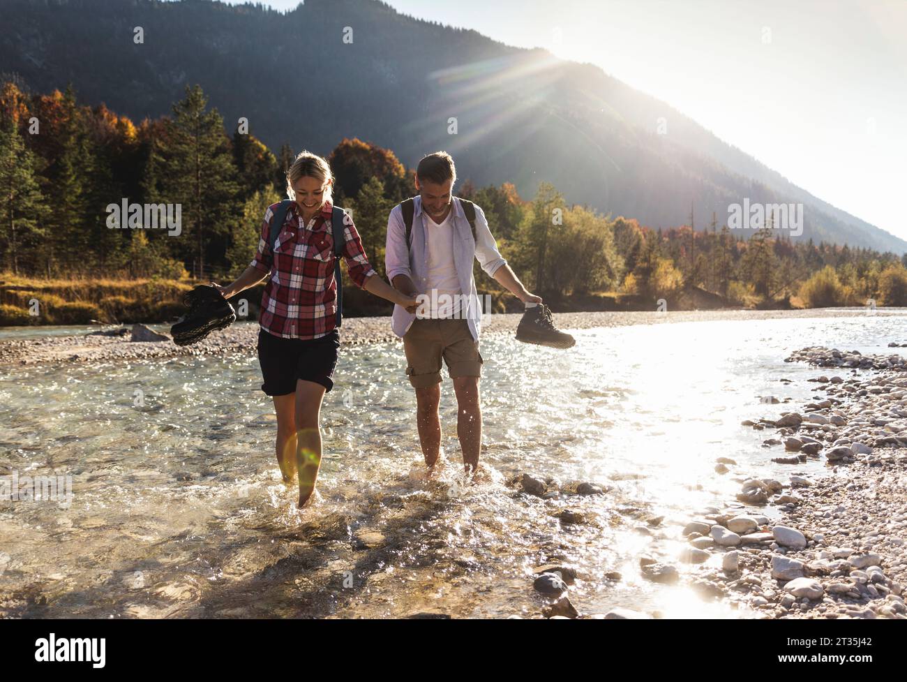 Austria, Alps, couple on a hiking trip wading in a brook Stock Photo ...