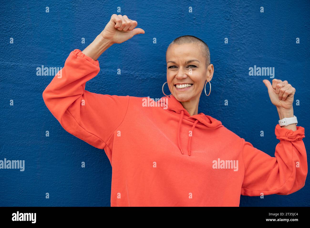 Happy woman with shaved head dancing in front of blue wall Stock Photo ...