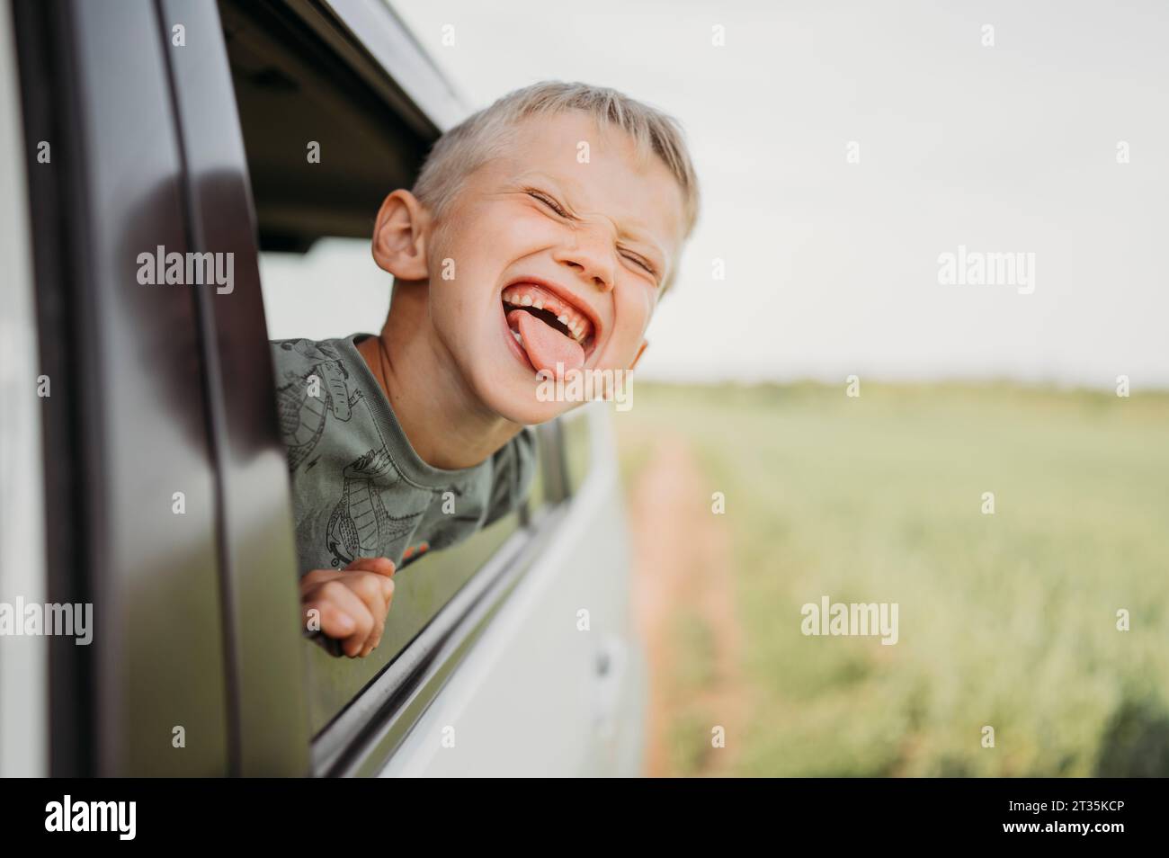 Smiling boy with tongue out looking outside car window Stock Photo - Alamy