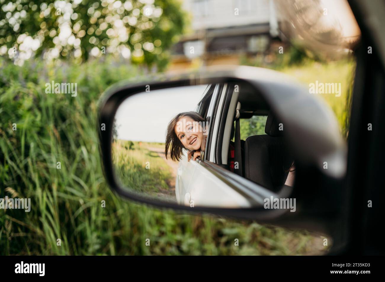 Reflection of boy looking out of car window in side-view mirror Stock ...