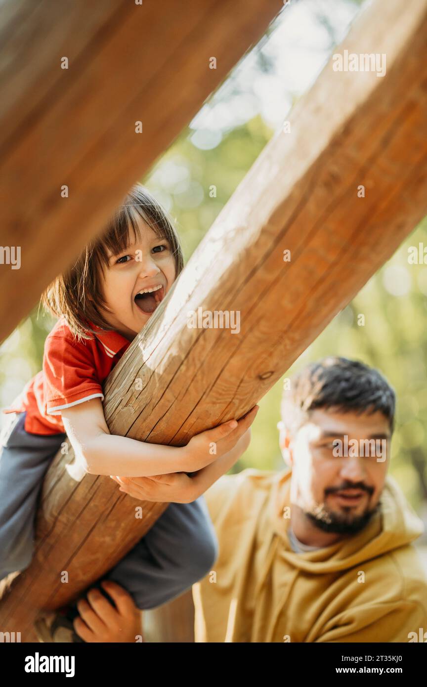 Cheerful boy having fun hanging on log Stock Photo - Alamy