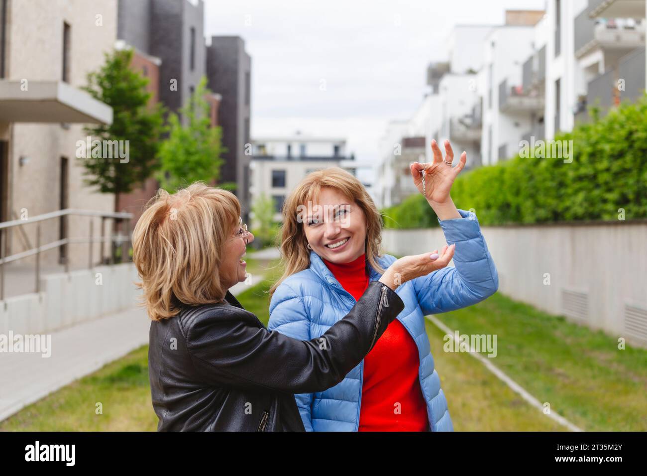 Happy daughter giving key to mother near residential area Stock Photo ...