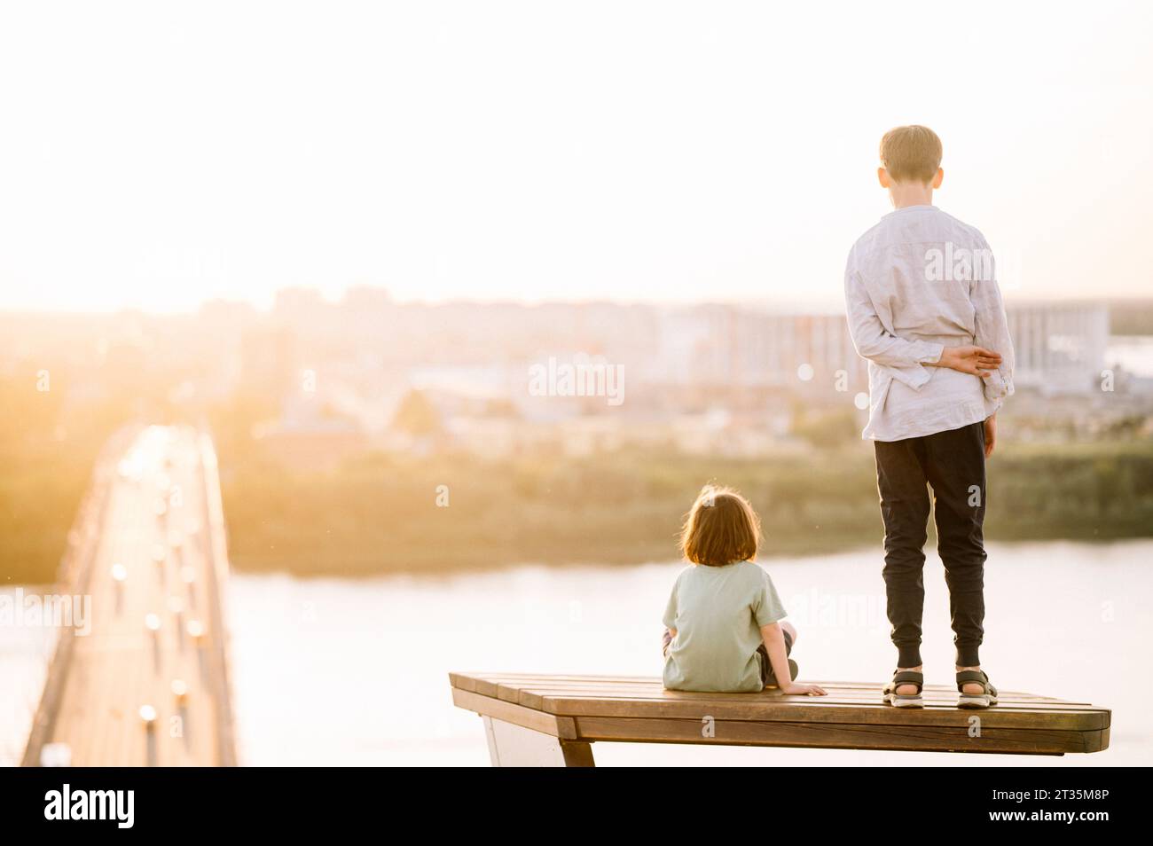 Boy with brother standing on platform at riverbank Stock Photo - Alamy