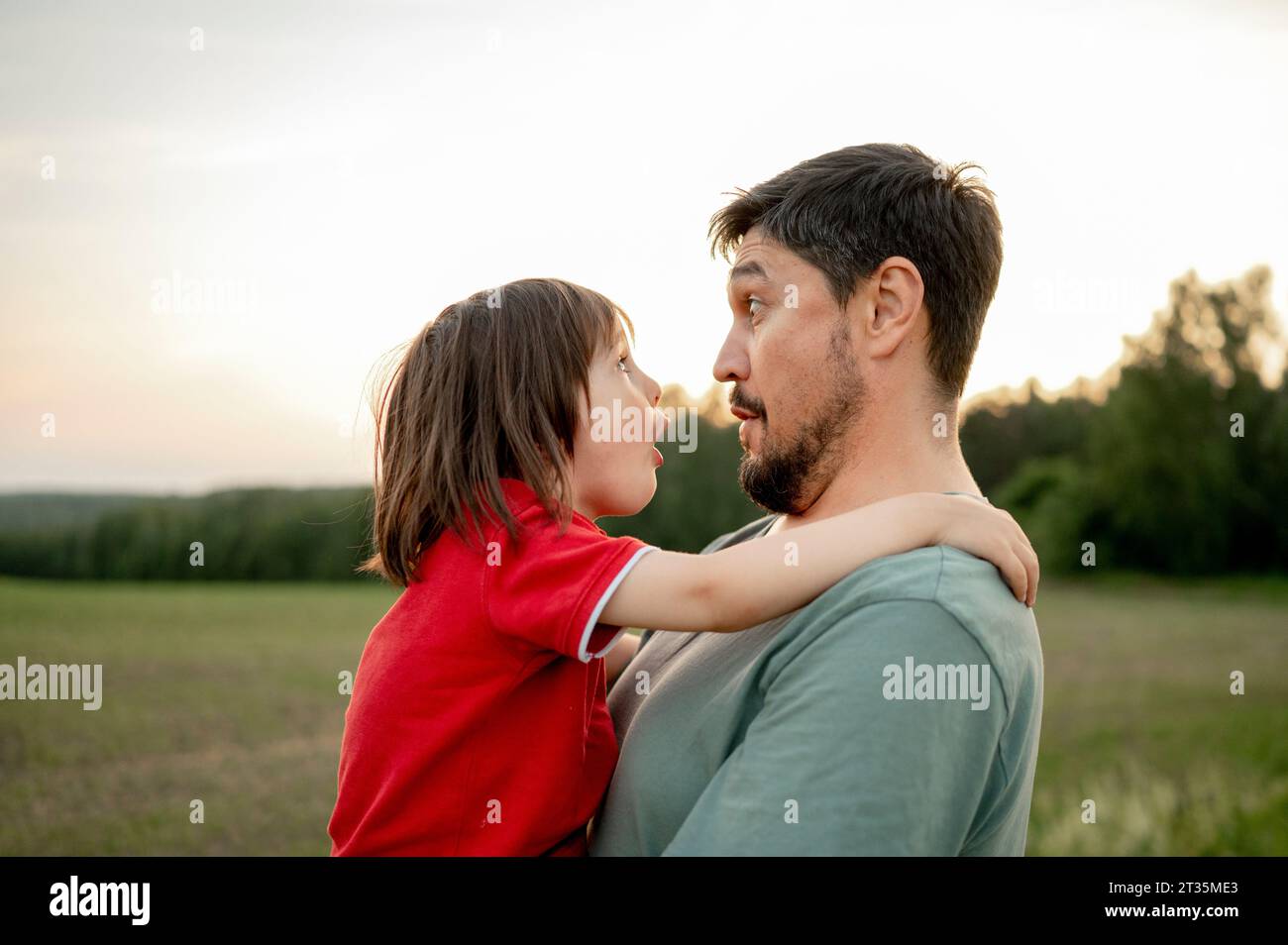 Surprised father carrying son in field Stock Photo - Alamy