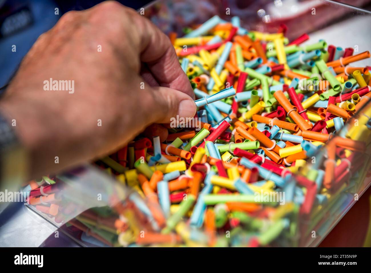 Hand of man choosing from multi colored raffle tickets Stock Photo - Alamy