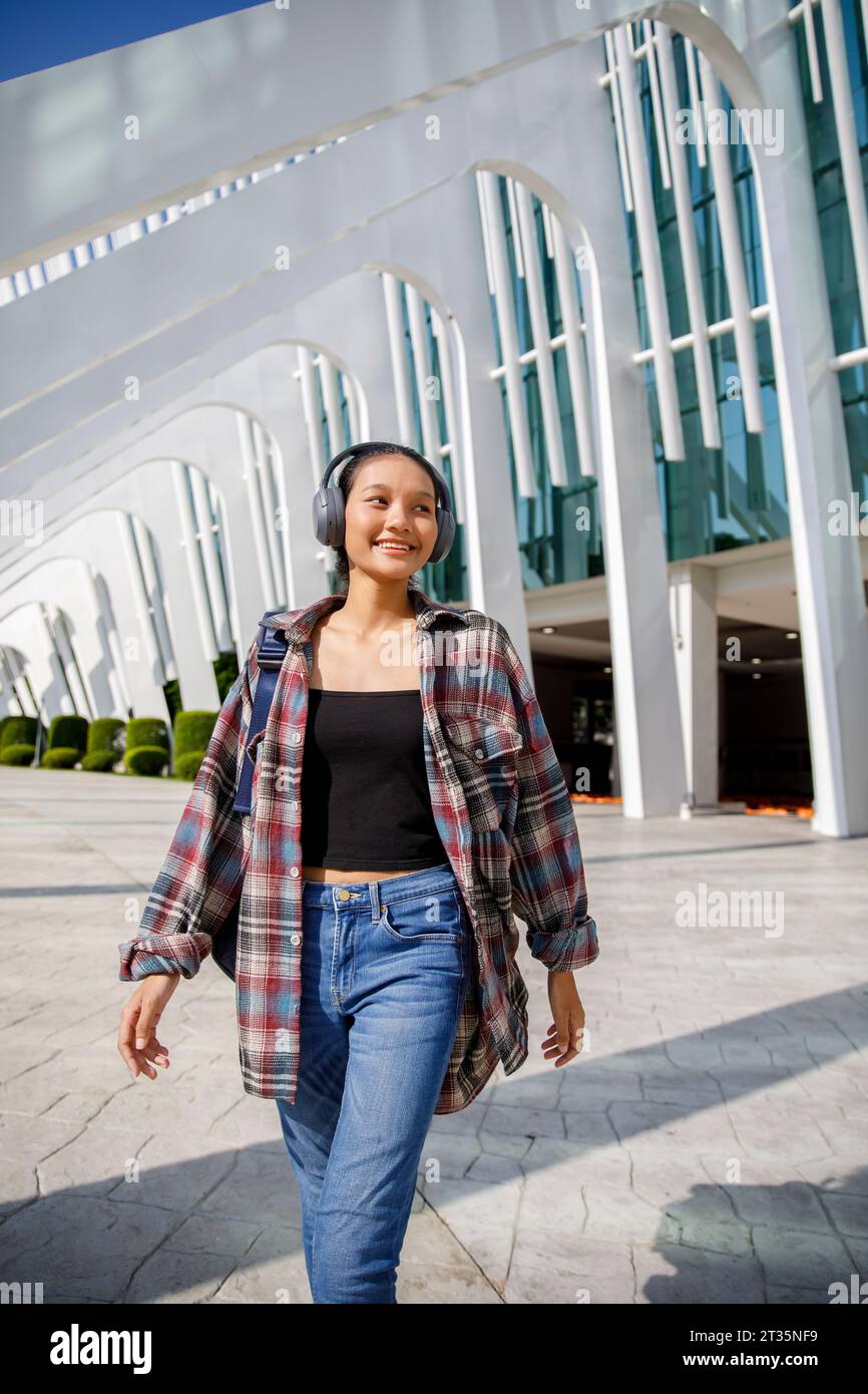 Smiling student walking in front of university building Stock Photo - Alamy