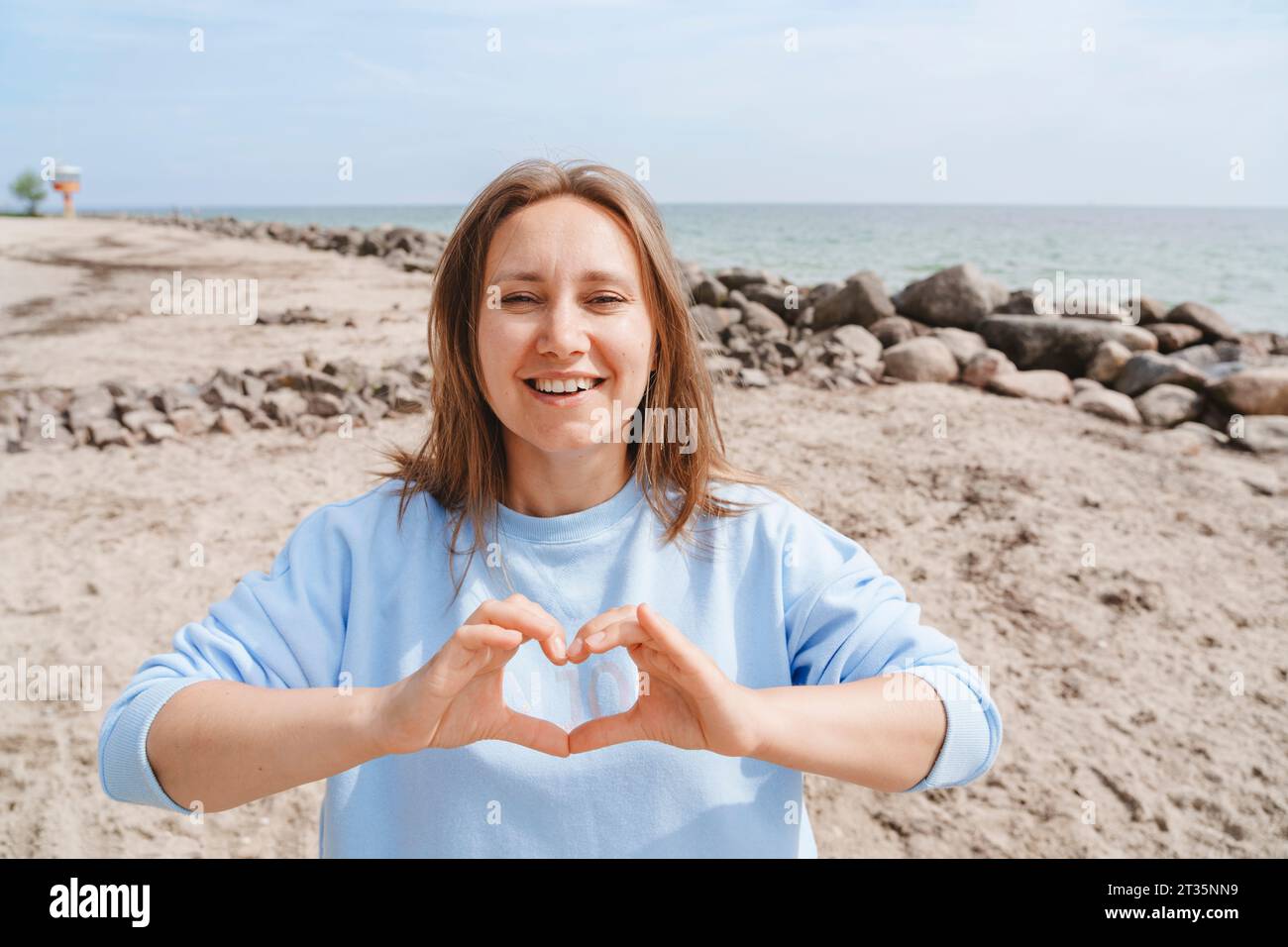 Smiling woman showing heart sign hi-res stock photography and images ...