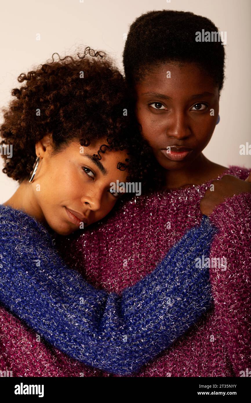 Young women hugging against beige background Stock Photo - Alamy