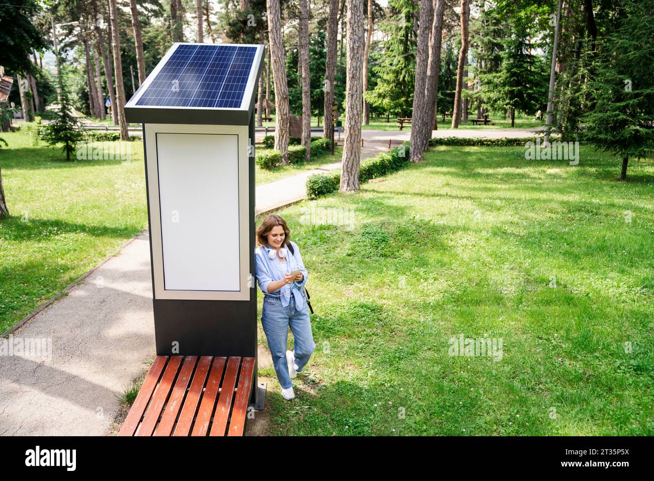 Woman surfing net through smart phone near solar charging point at park Stock Photo - Alamy