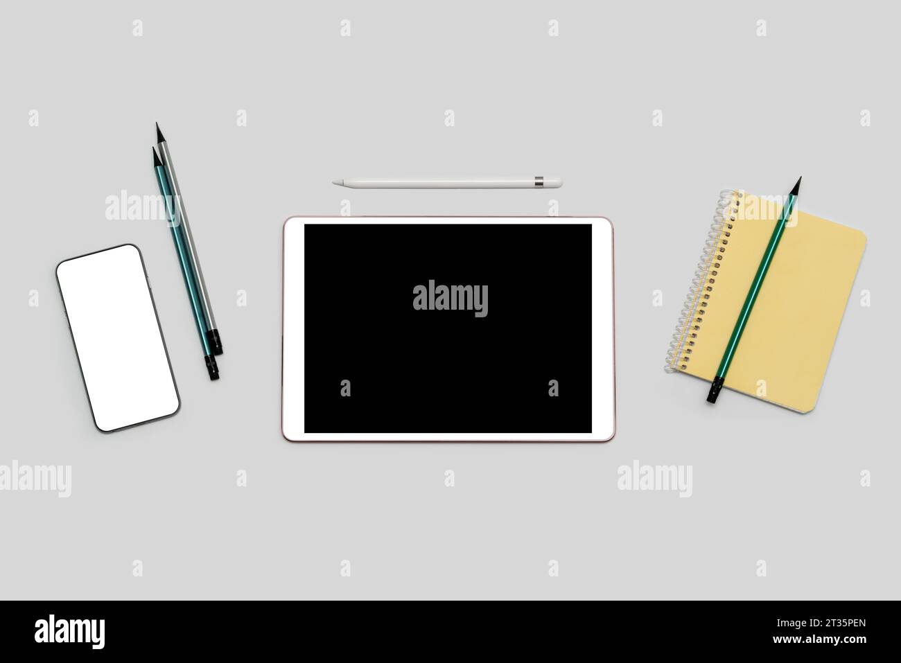 Tablet and phone with isolated screen, notepad, pencils lying on table ...