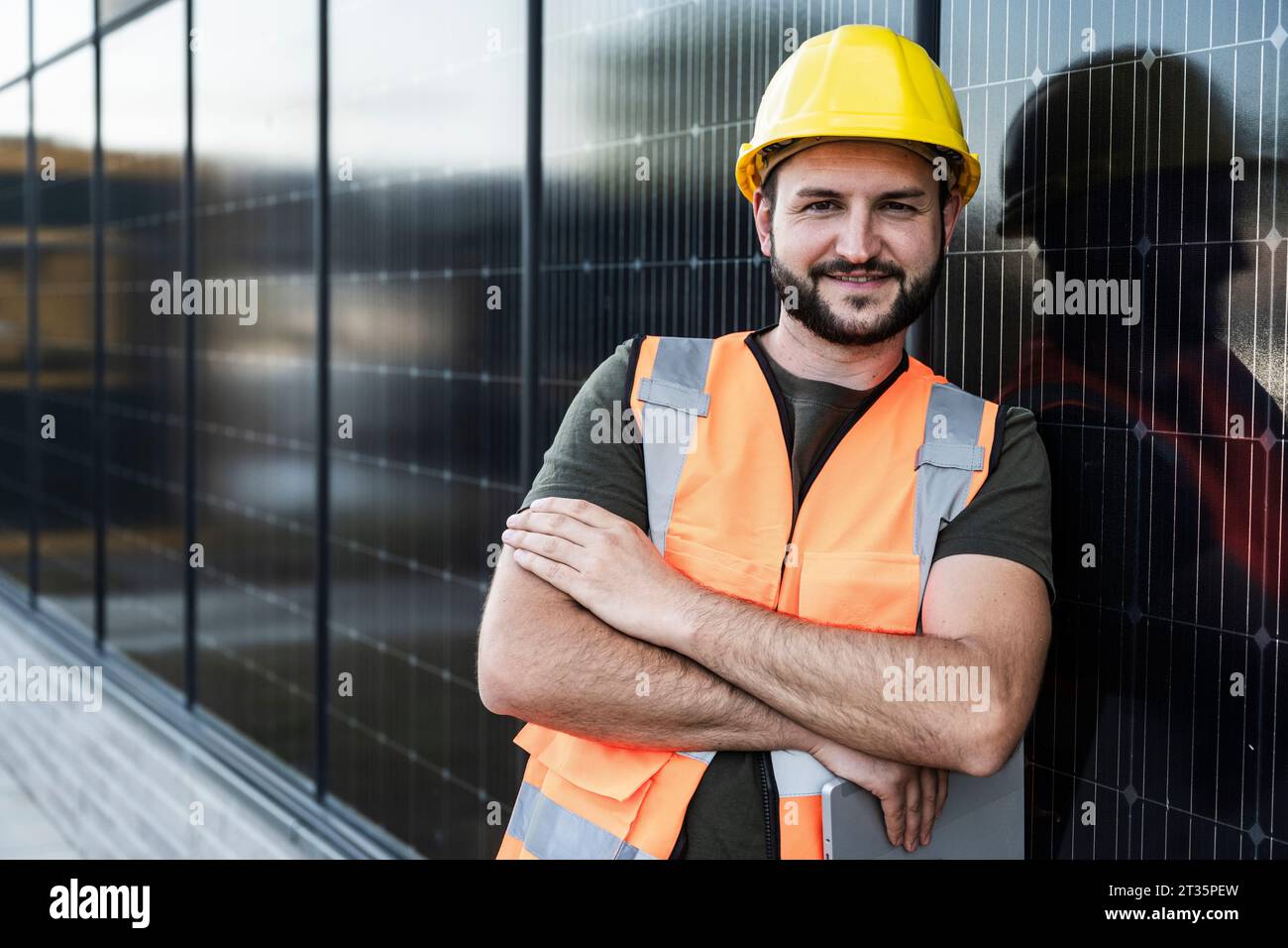 Smiling engineer leaning on solar panels Stock Photo - Alamy
