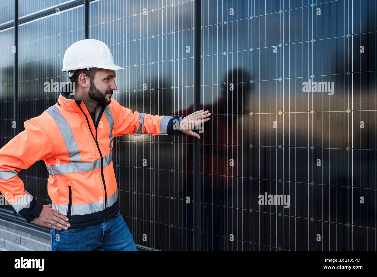 Engineer with hand on hip examining solar panels Stock Photo - Alamy