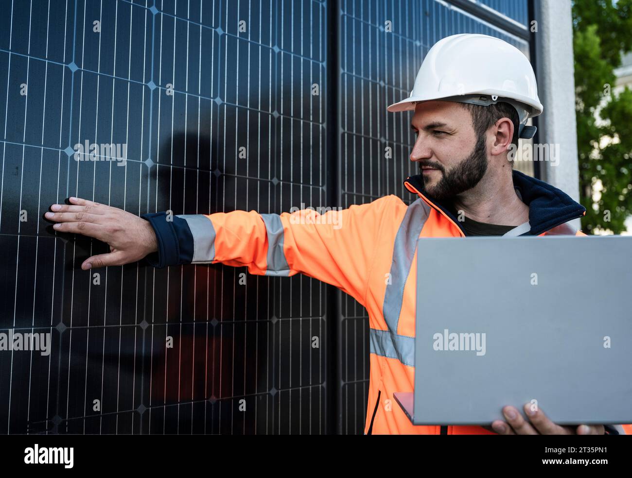 Engineer holding laptop and touching solar panels Stock Photo - Alamy