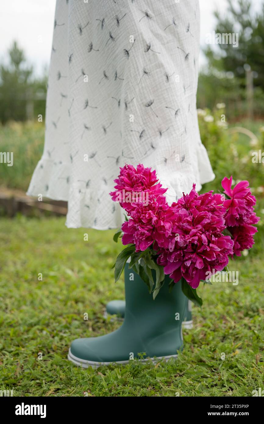 Girl standing with flowers in rubber boot Stock Photo - Alamy