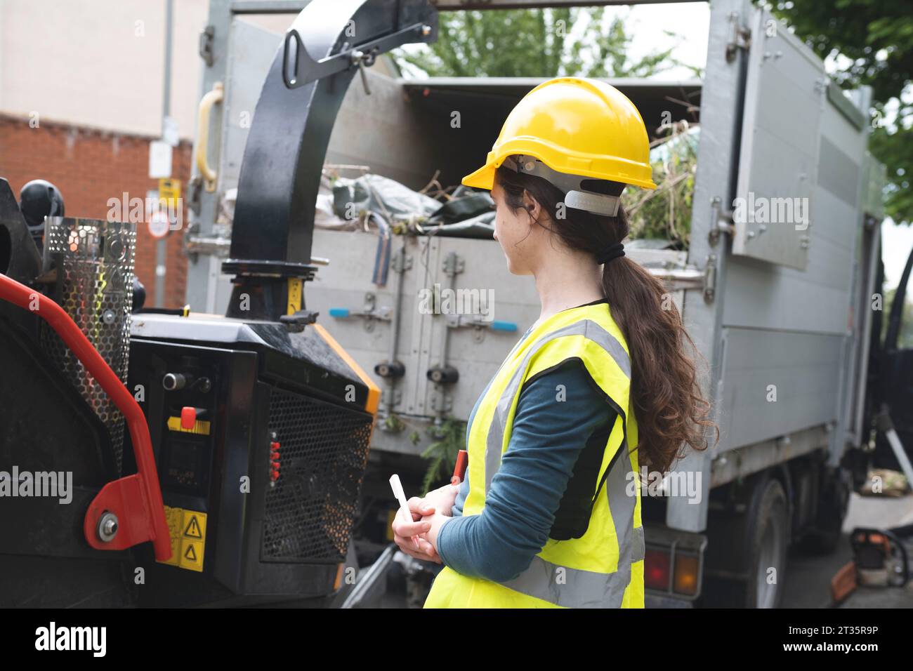 Blue collar worker looking at dumper truck picking up garbage Stock ...