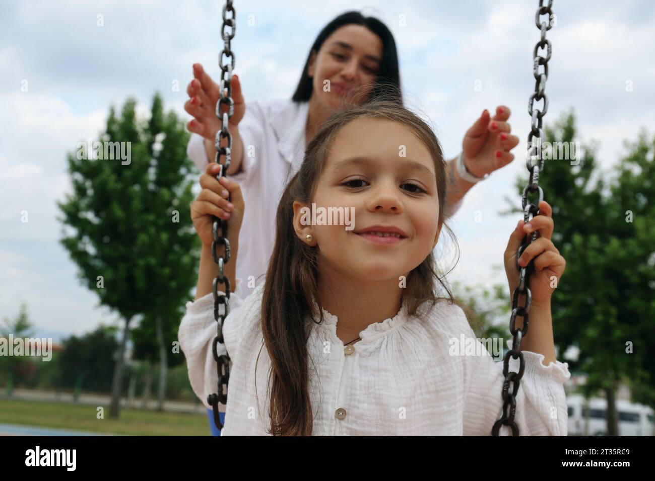Happy children swinging in park hi-res stock photography and images - Alamy