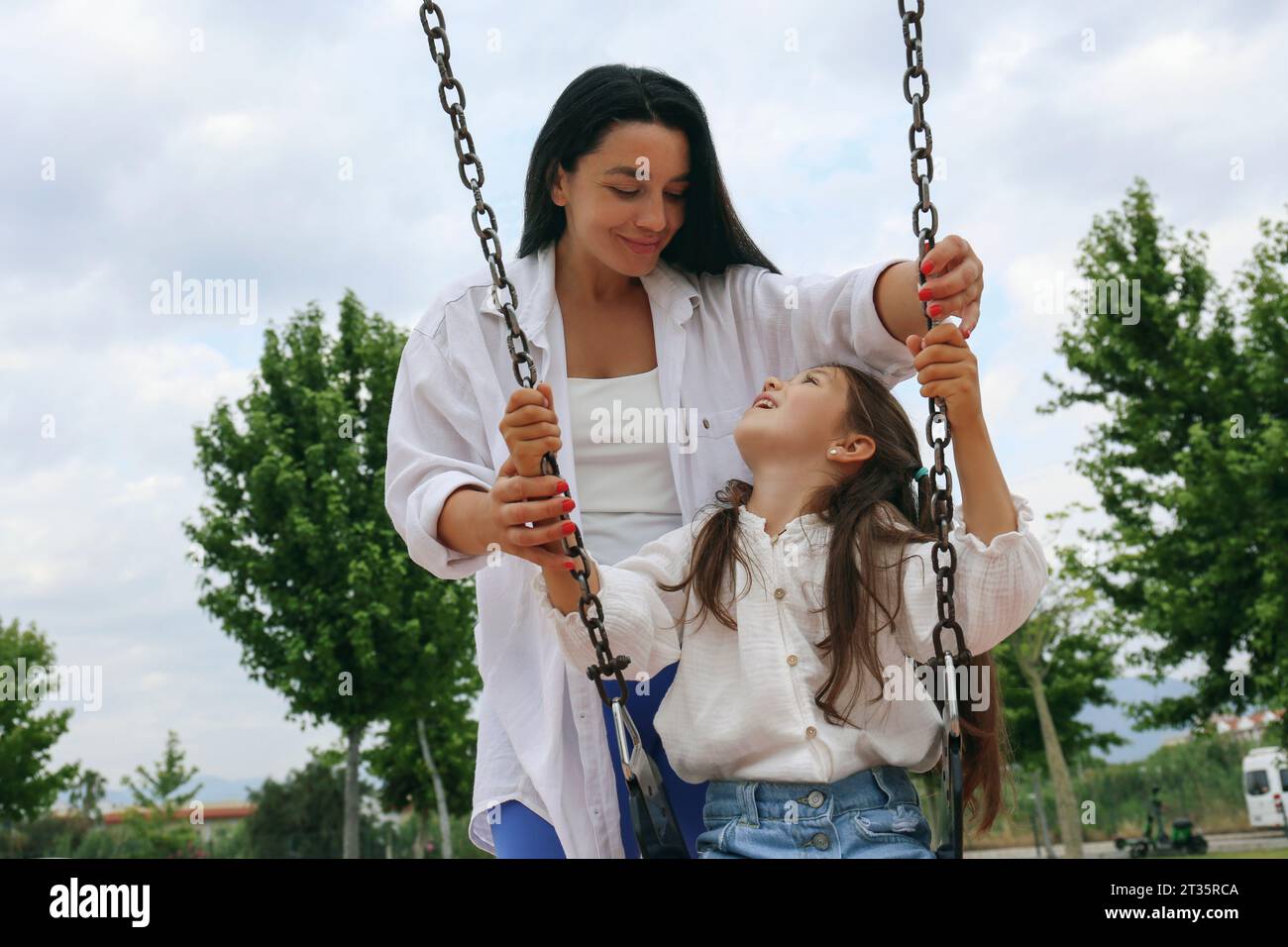 Smiling mother with daughter swinging on swing Stock Photo - Alamy