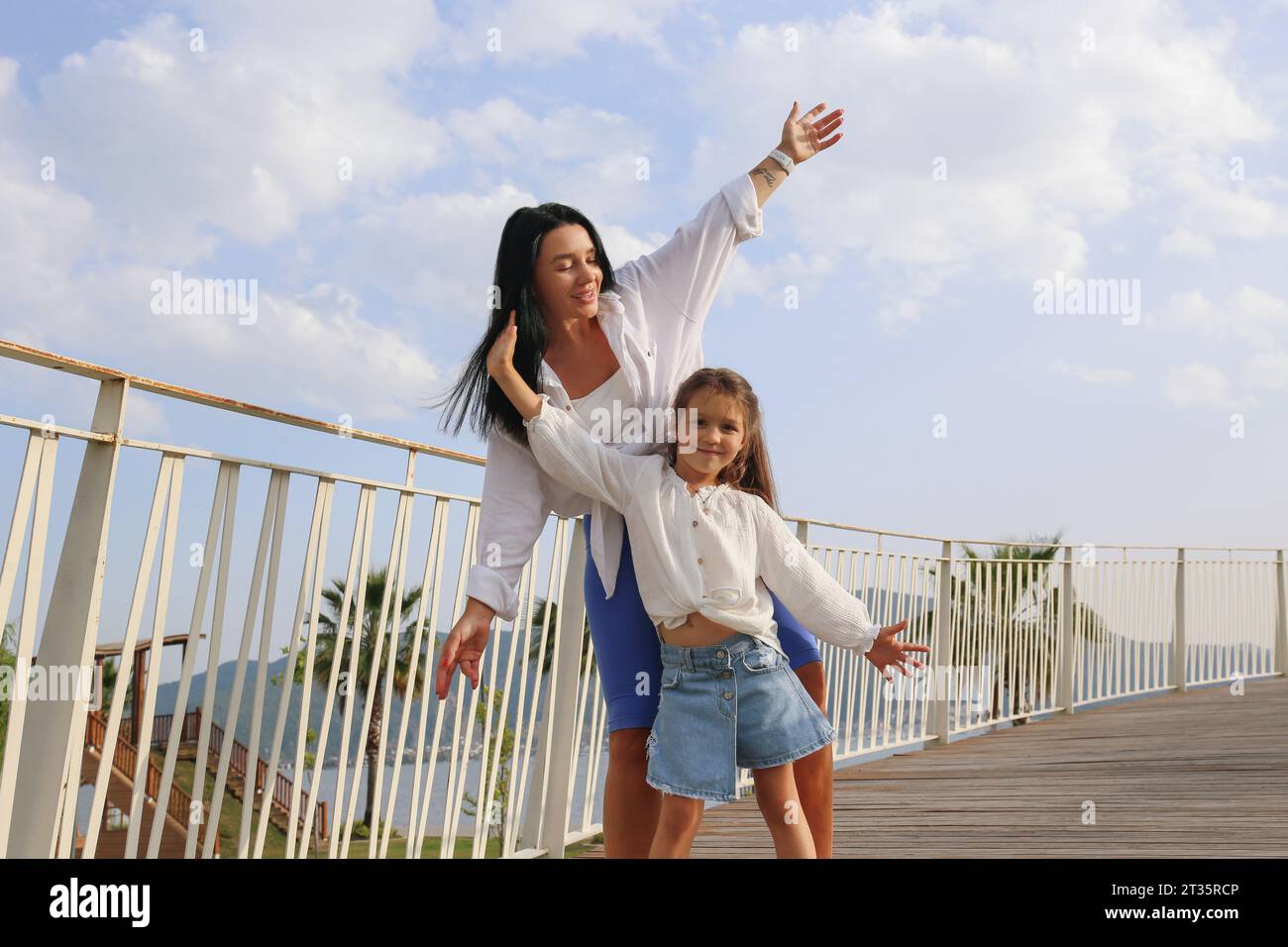 Happy mother and daughter dancing with arms raised on sunny day Stock ...