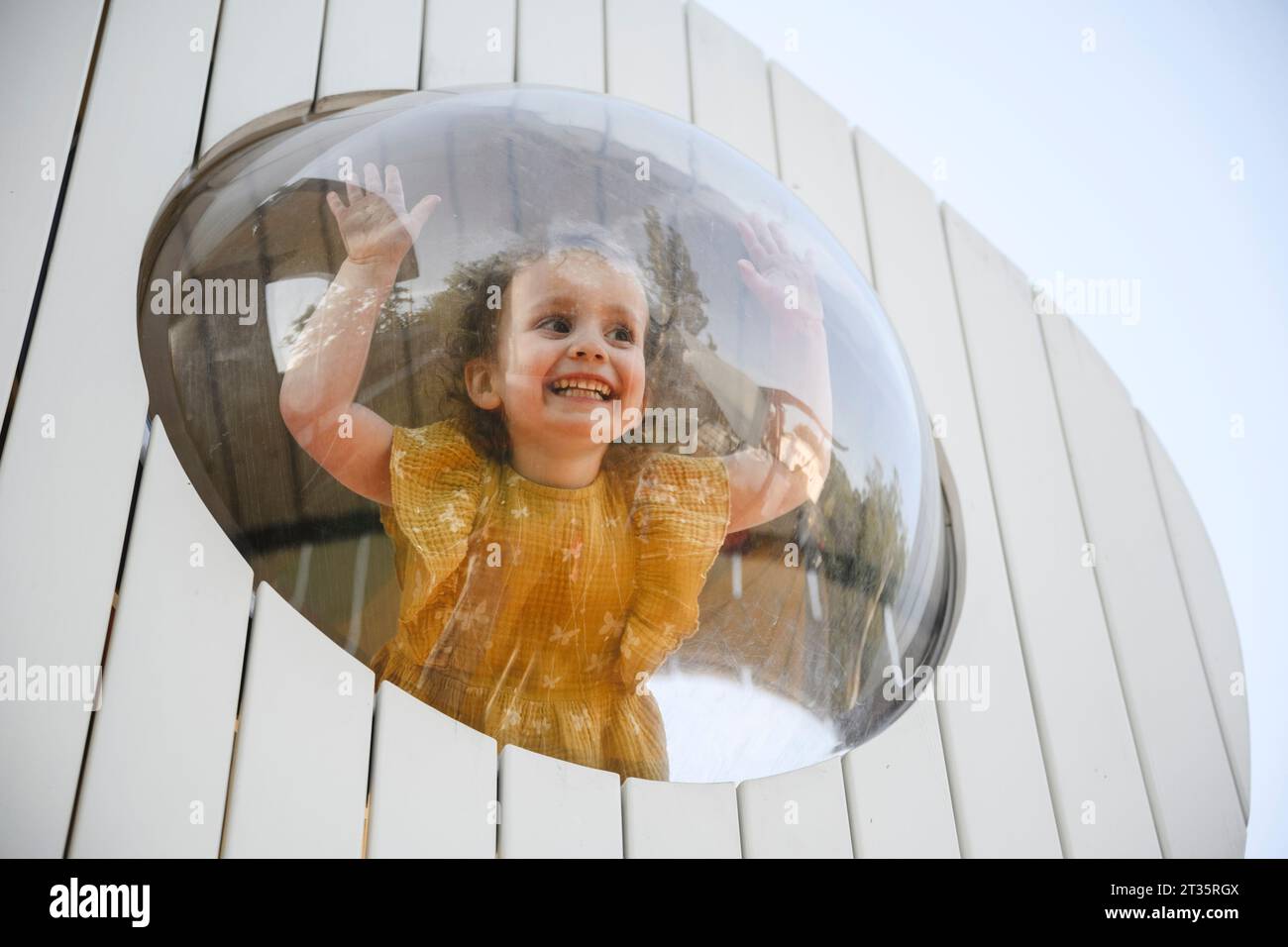 Carefree girl leaning on glass window of house Stock Photo - Alamy