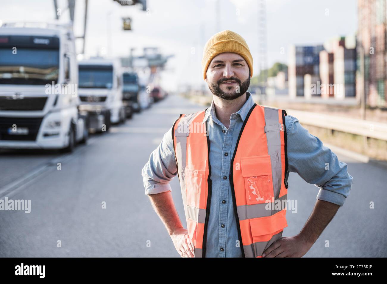 Smiling truck driver standing with hands on hip Stock Photo - Alamy