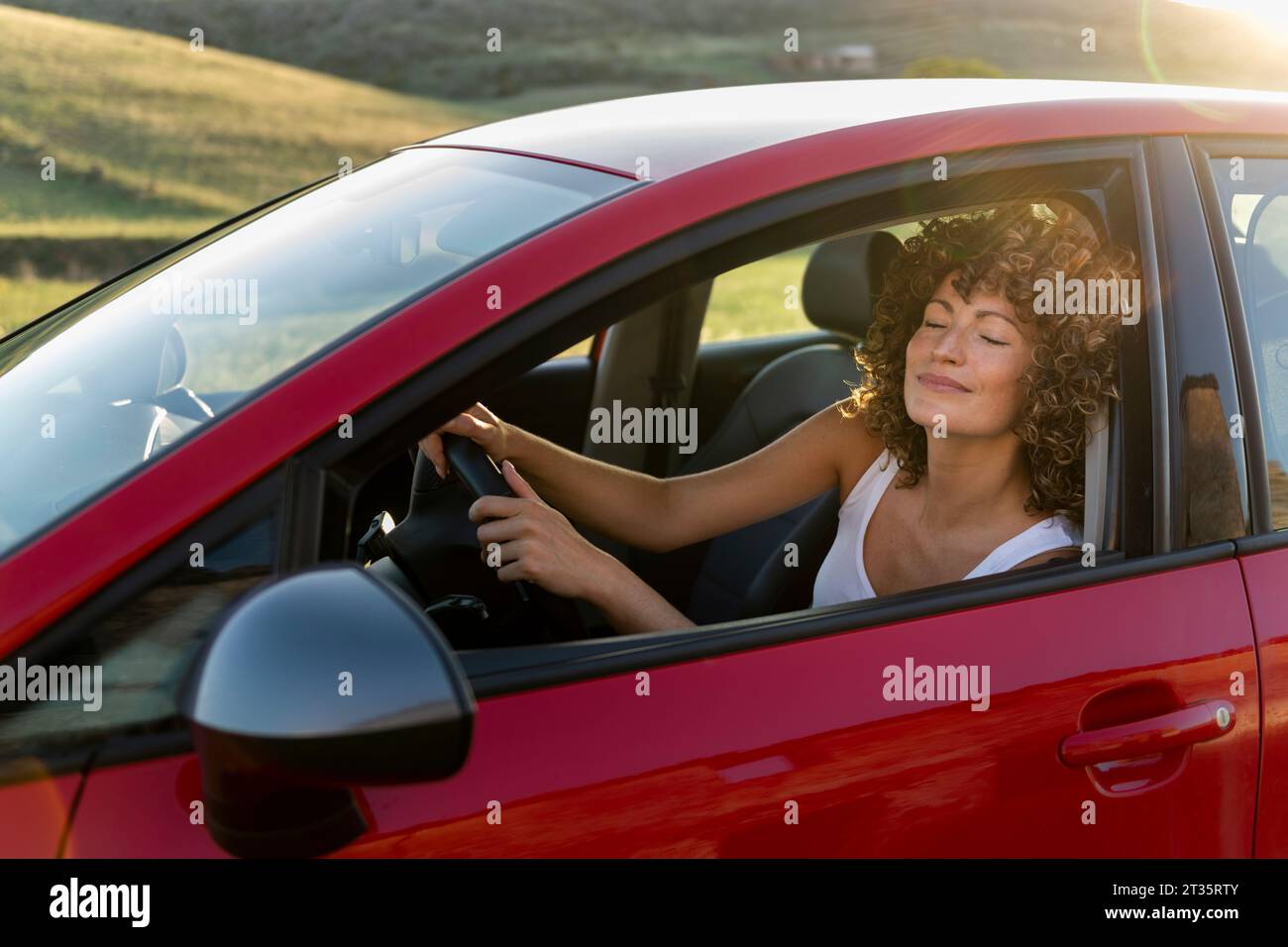 Smiling woman with eyes closed driving red car Stock Photo - Alamy