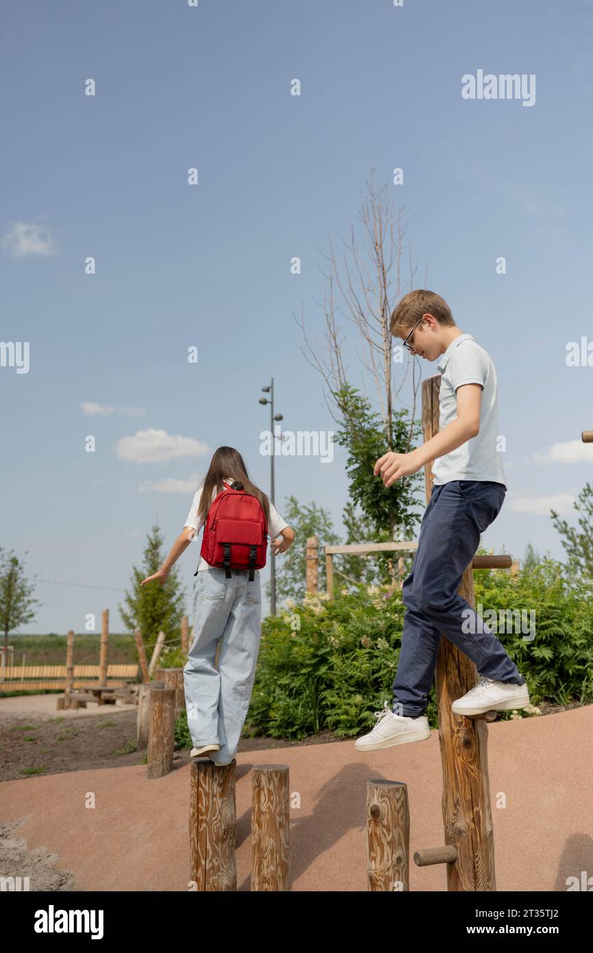 Friends balancing on wooden pole at playground Stock Photo - Alamy