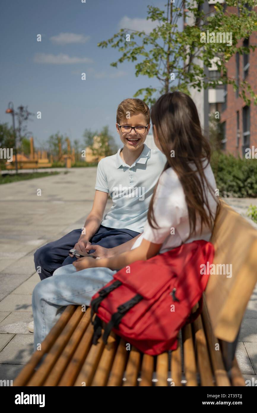 Smiling friends having discussion sitting on bench at park Stock Photo ...