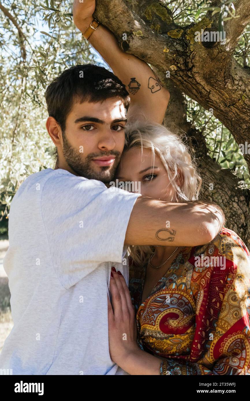Young man hugging woman under tree on sunny day Stock Photo - Alamy