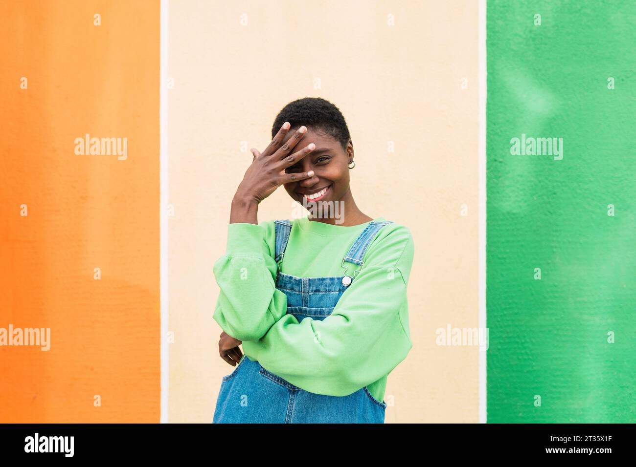 Happy young woman touching forehead standing in front of multi colored ...