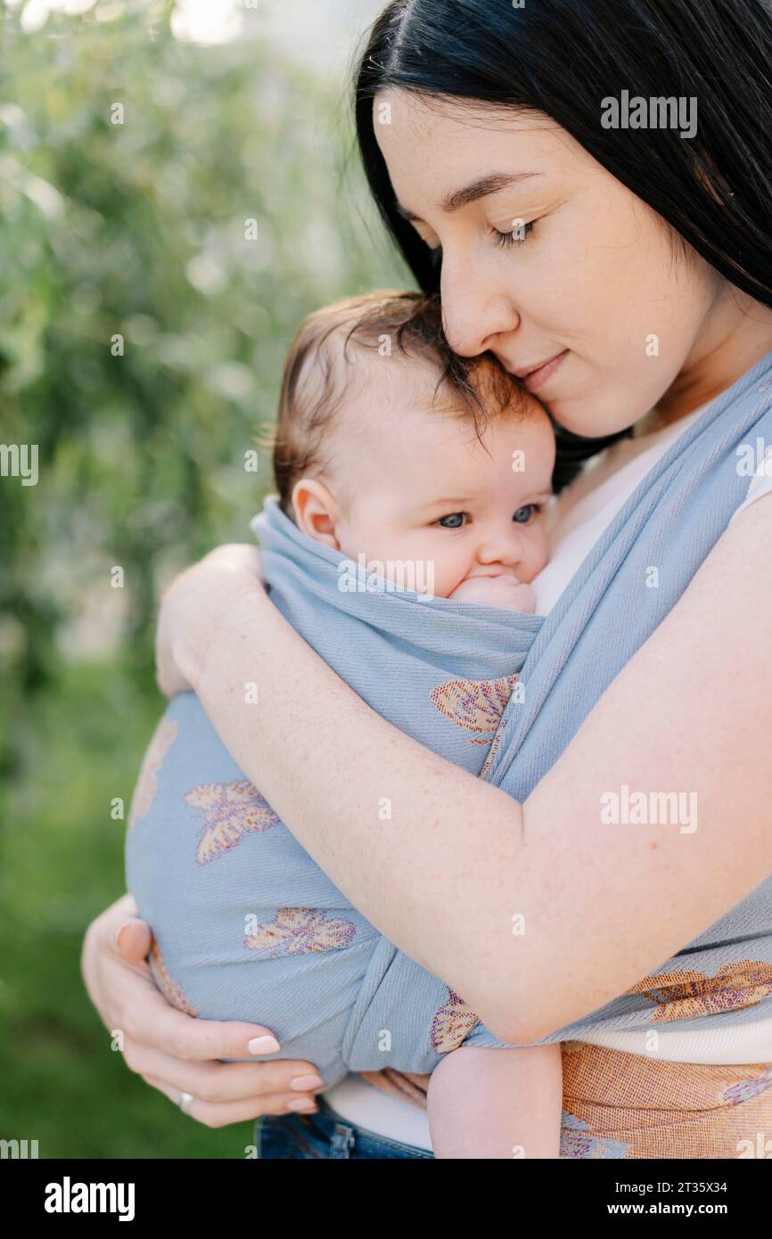 Affectionate mother embracing daughter in baby sling Stock Photo - Alamy