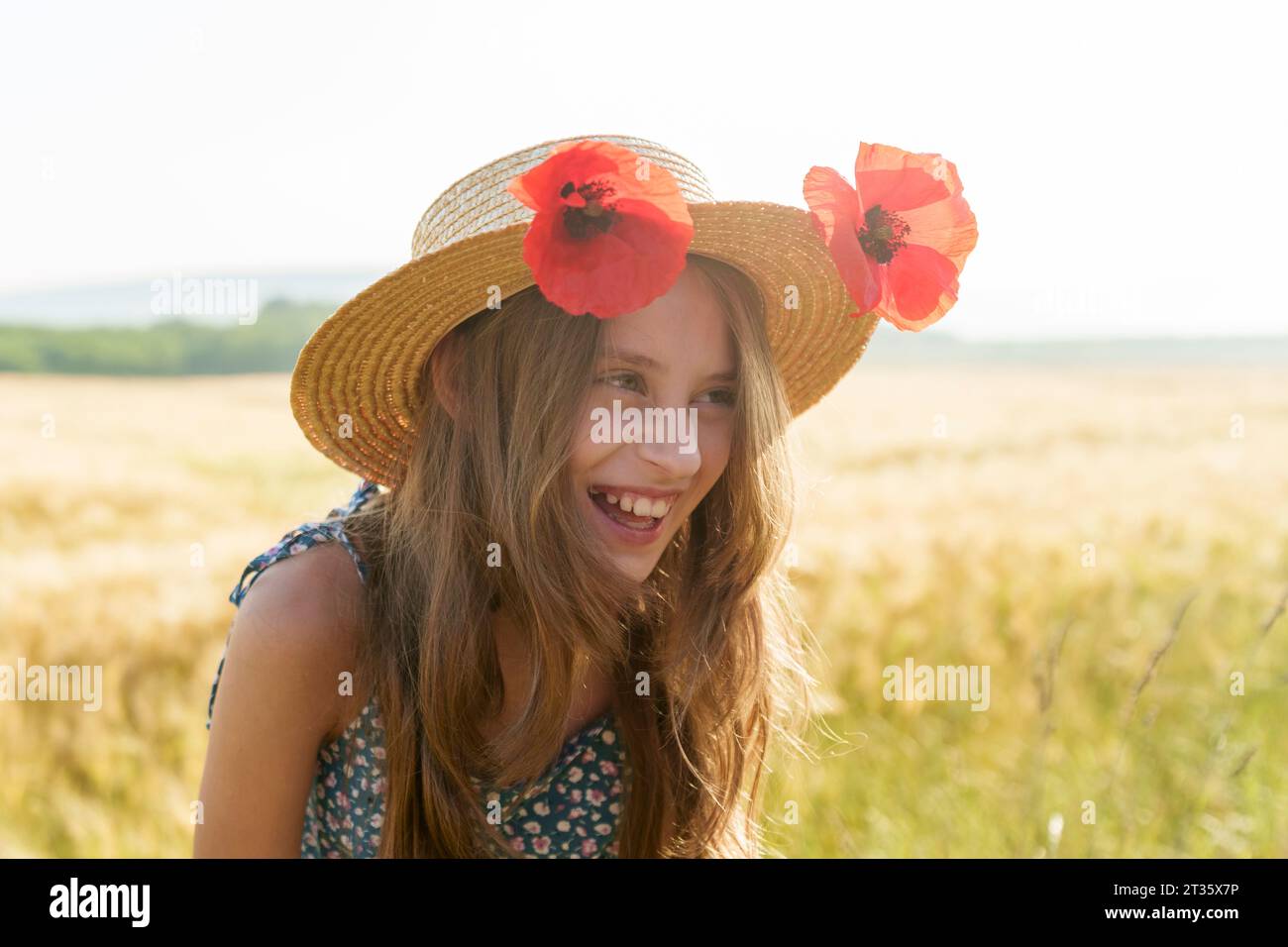 Cheerful girl wearing hat with red poppies at field Stock Photo - Alamy