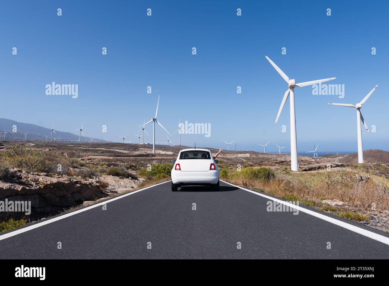 Car moving on road amidst wind turbines under blue sky Stock Photo - Alamy