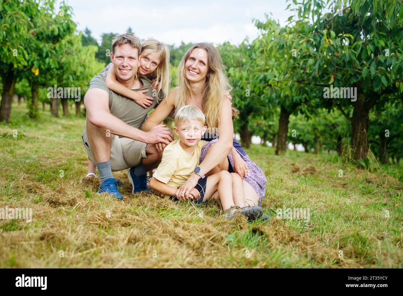 Happy family together admist cherry trees in garden Stock Photo - Alamy