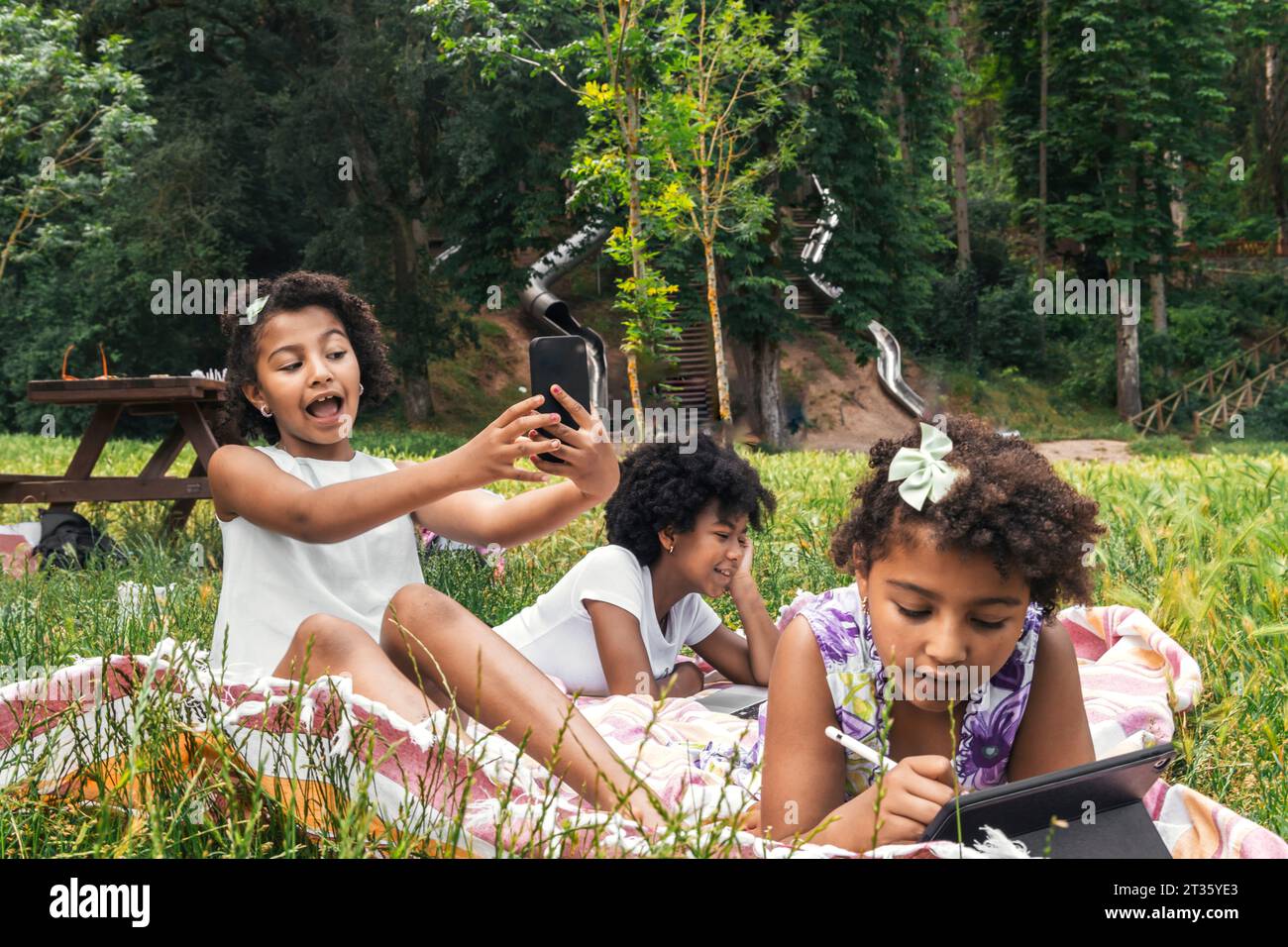 Girl clicking selfie with smart phone next to sisters in garden Stock ...