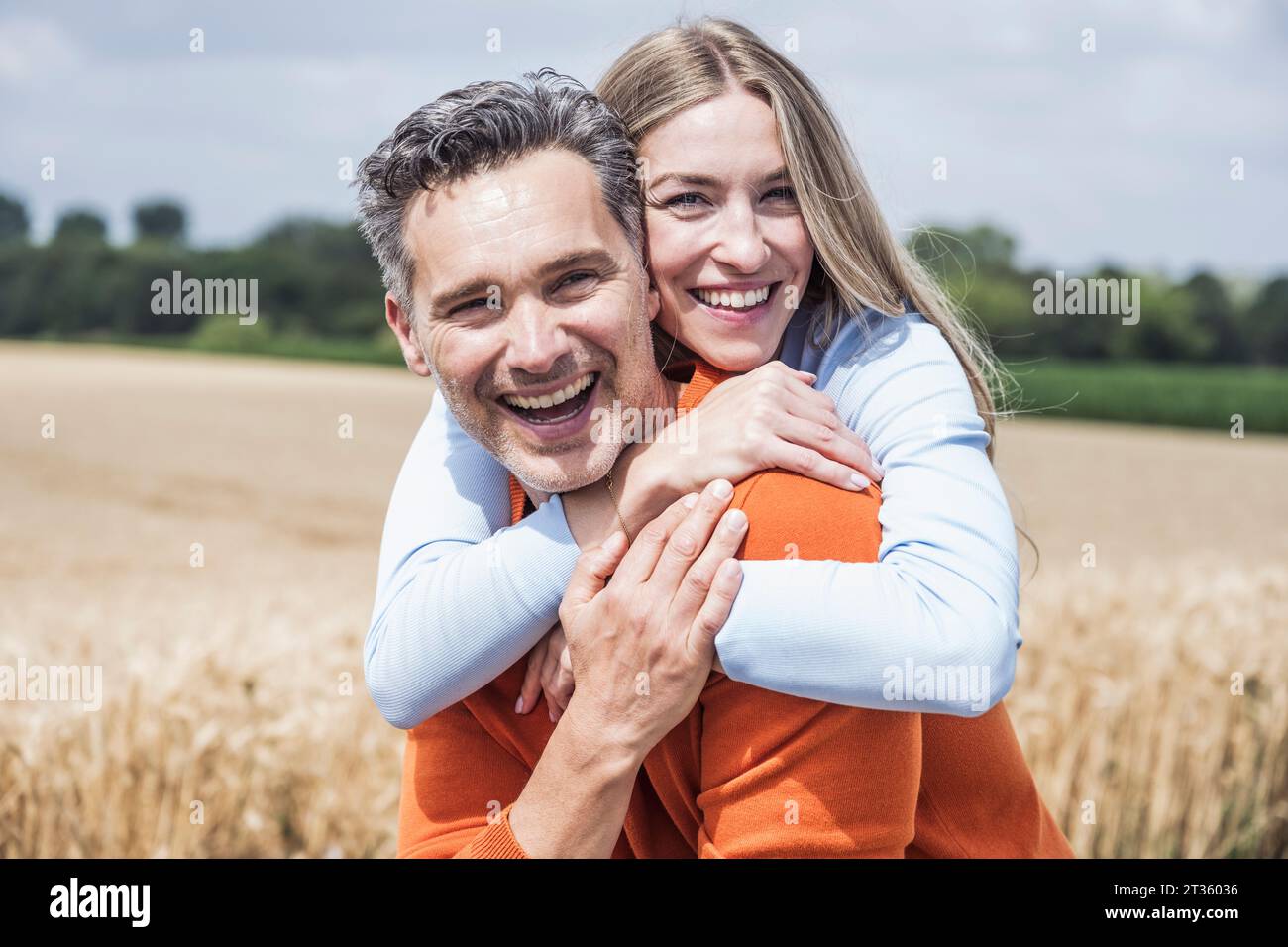 Happy woman embracing man in front of field Stock Photo - Alamy