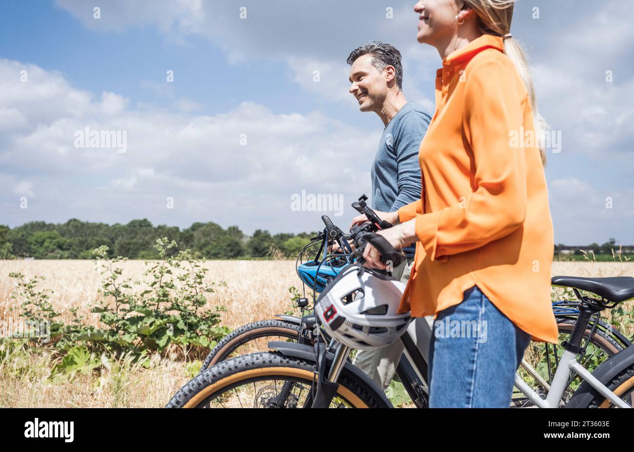 Couple wheeling bicycles near field Stock Photo - Alamy