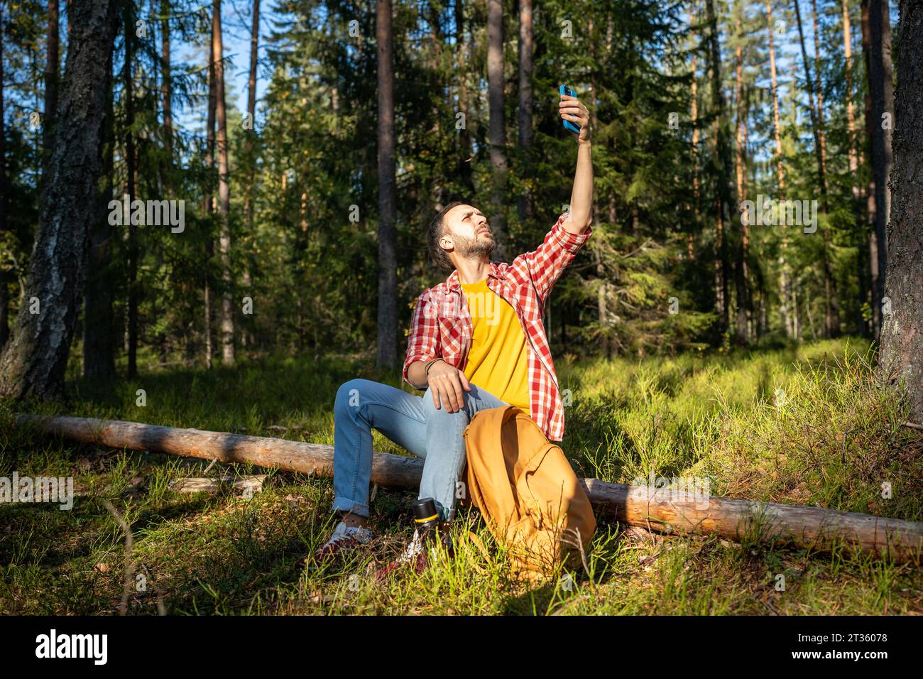 Concentrated young man resting on timber, trying to find internet ...