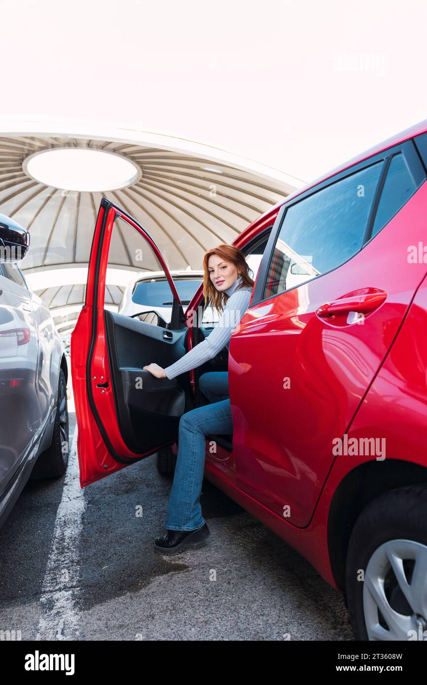 Woman getting out from red car Stock Photo - Alamy
