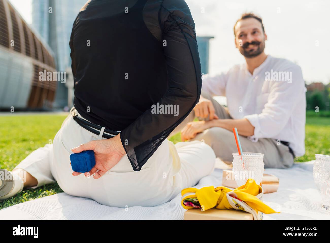 Woman hiding jewelry box behind back in front of happy man Stock Photo ...