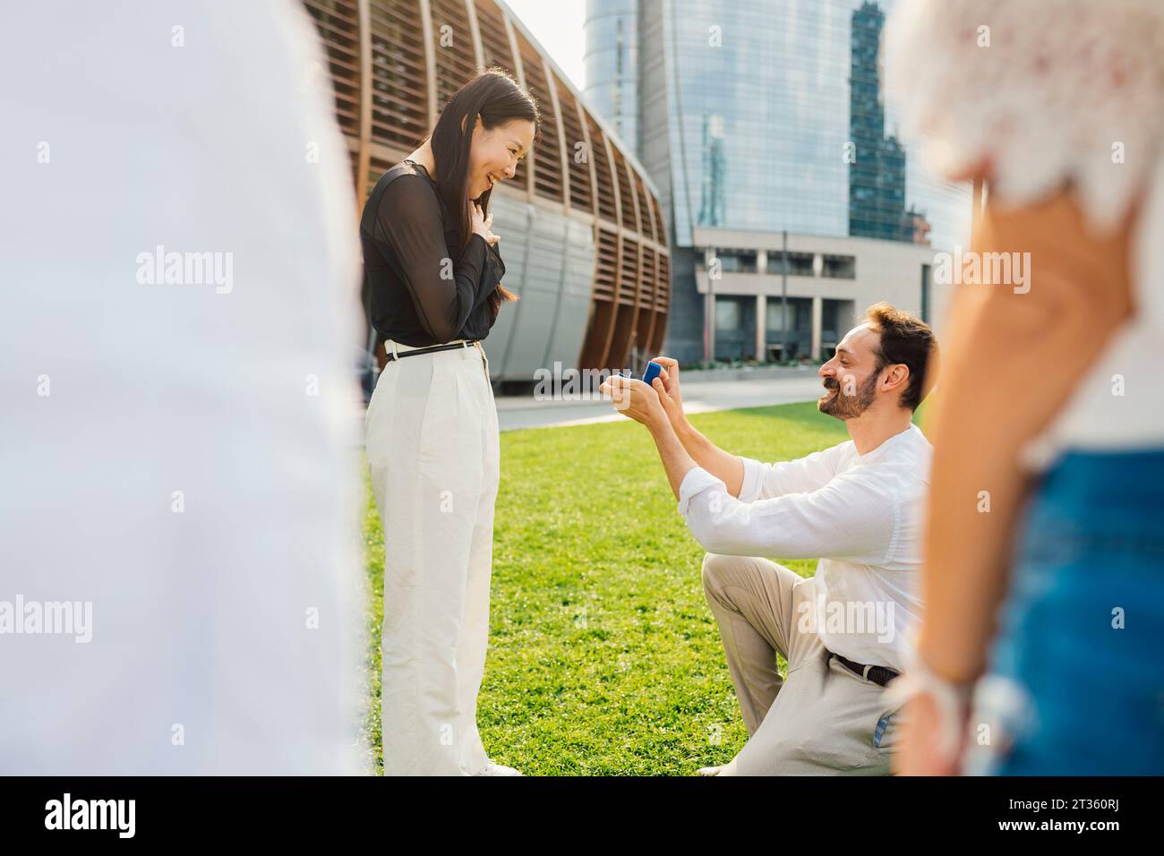 Smiling man proposing woman with ring at park Stock Photo - Alamy