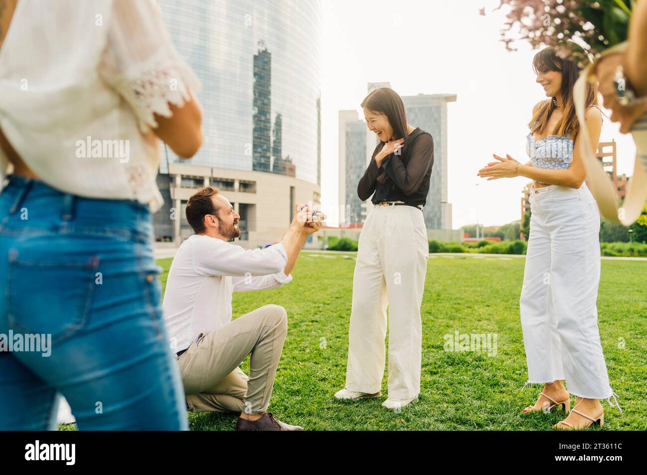 Happy man proposing woman with ring in front of buildings Stock Photo ...