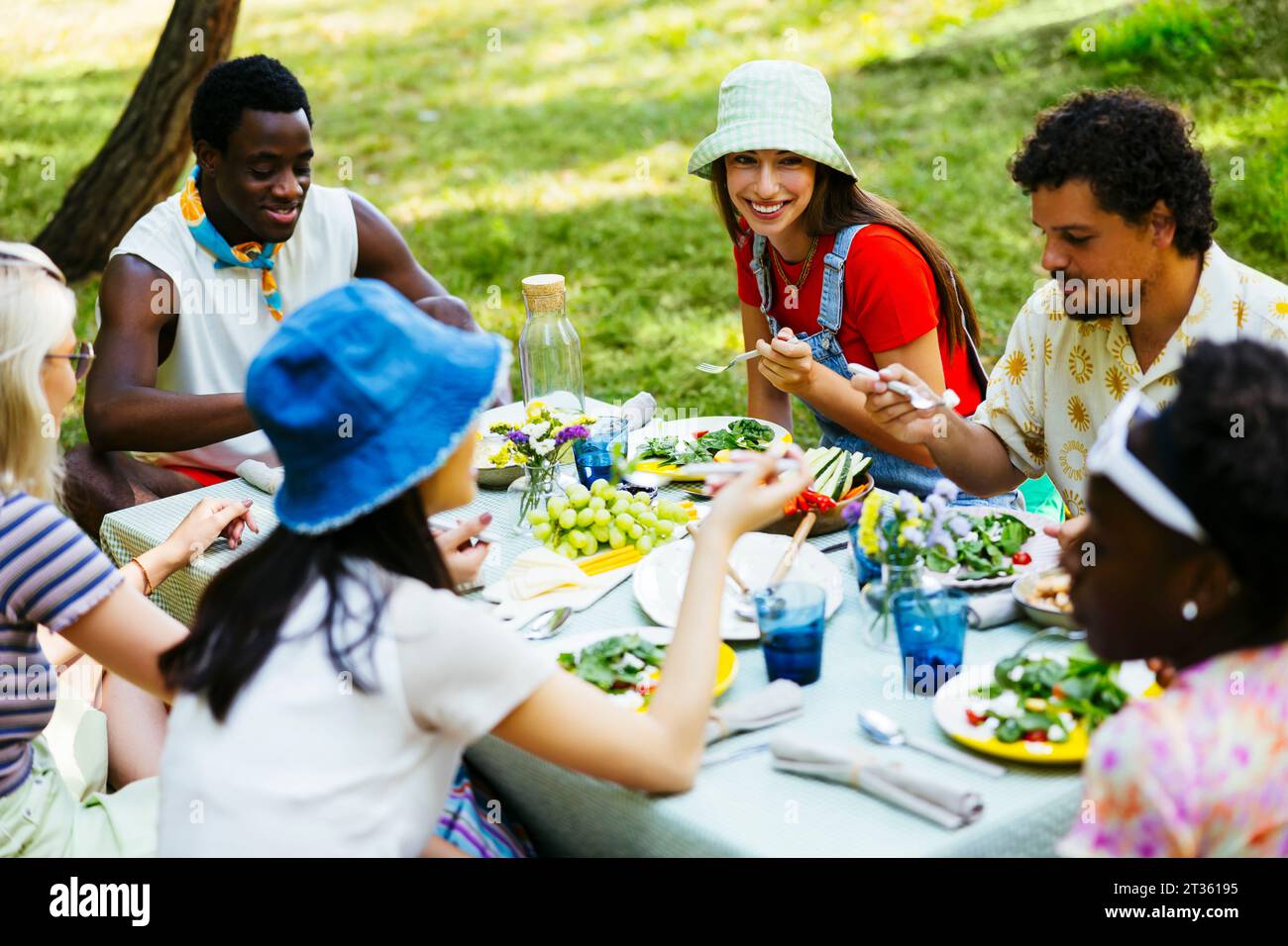 Smiling friends having conversation at picnic table in garden Stock ...
