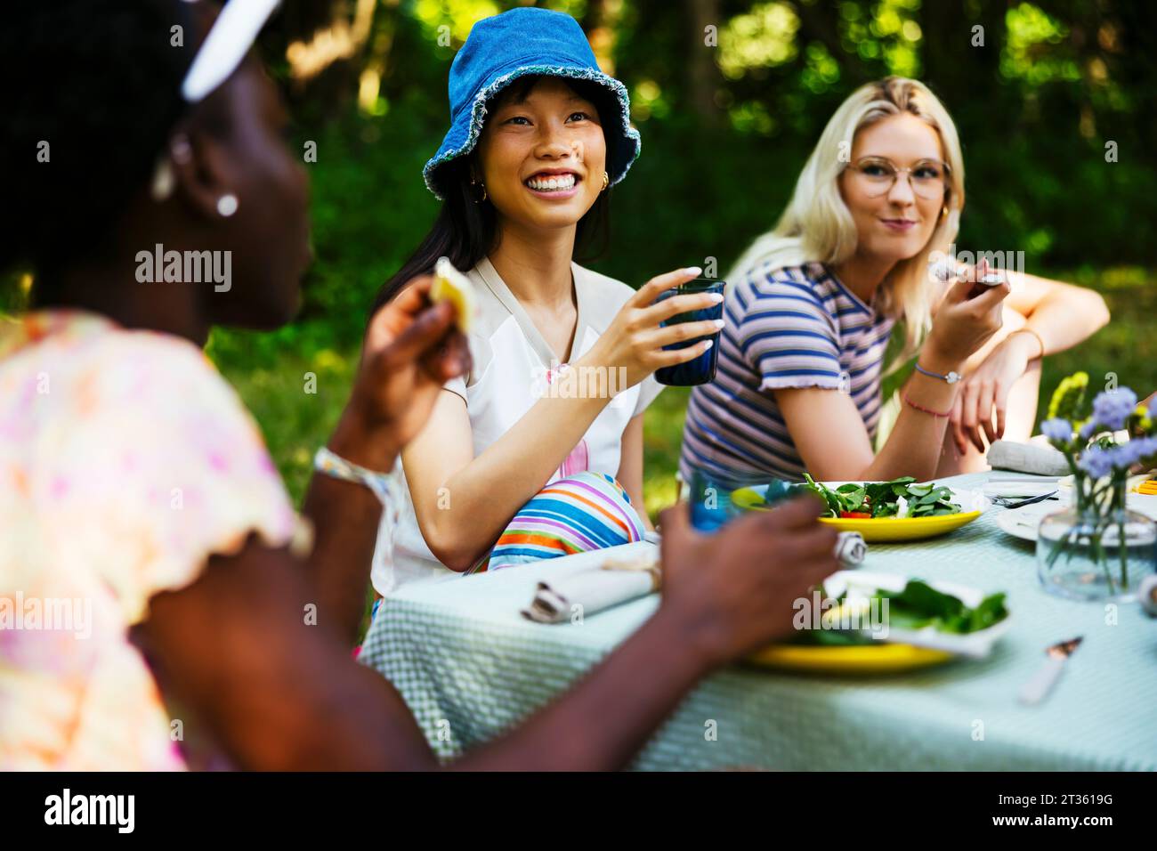Smiling friends having lunch at picnic table in garden Stock Photo - Alamy