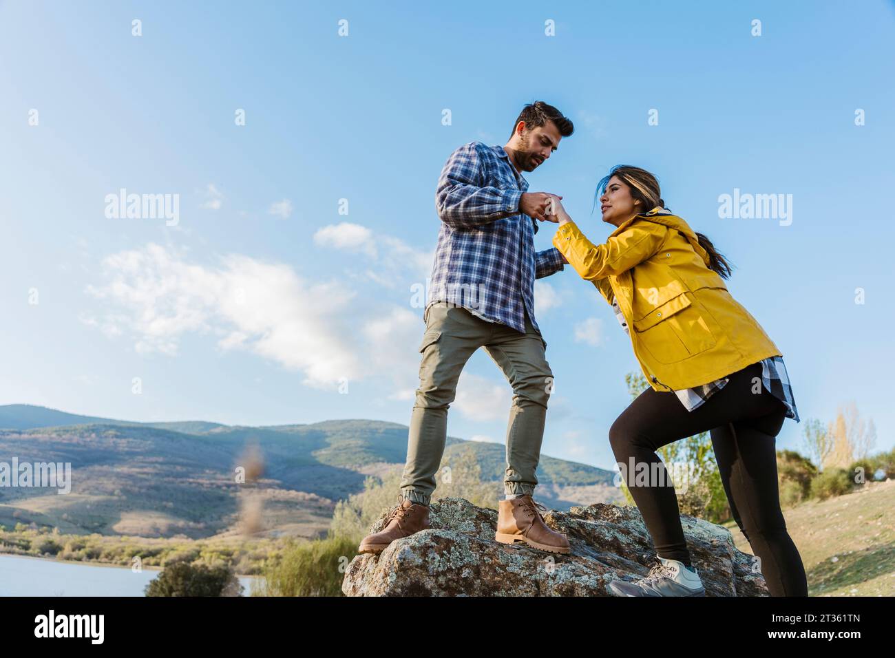 Boyfriend holding hands of girlfriend climbing on rock Stock Photo - Alamy