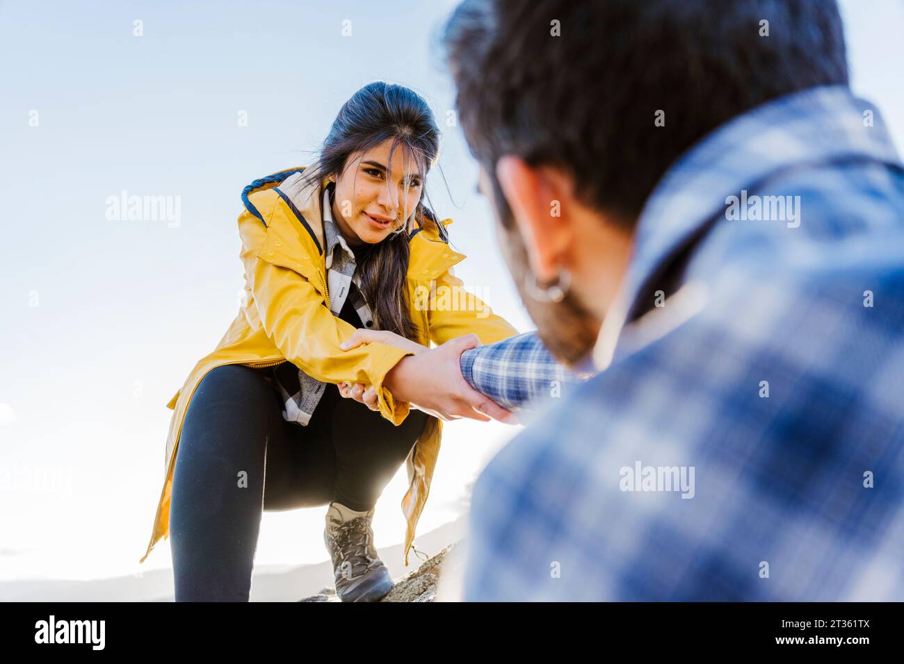 Girlfriend helping boyfriend climbing on rock Stock Photo - Alamy