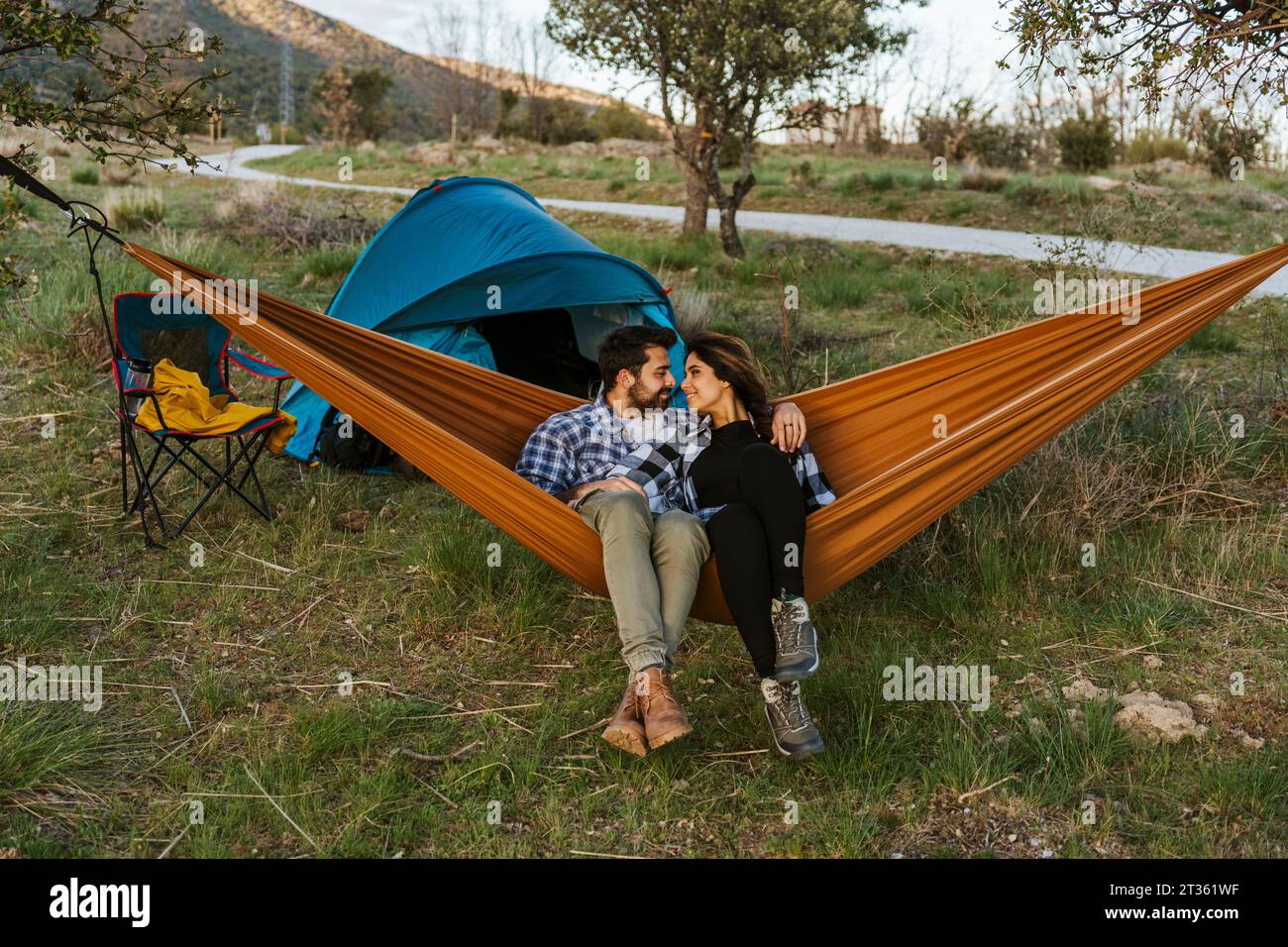 Romantic couple sitting in hammock near tent Stock Photo - Alamy